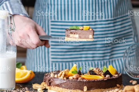 과자 요리사 손에 오렌지와 땅콩 초콜릿 케이크의 조각을 들고 채식주의자를 위한 건강 한 생 디저트 감귤류 과일에 대한 스톡 사진 및 기타 이미지 Istock
