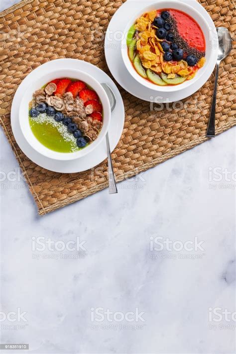 2 신선한 슬라이스 과일 밀 밀기 울 콘플레이크와 코코넛 칩 Chia의 종자 및 열매 건강 한 아침 식사는 시리얼과 딸기와 키 위에서 다른 스무디와 그릇 슈퍼 식품입니다