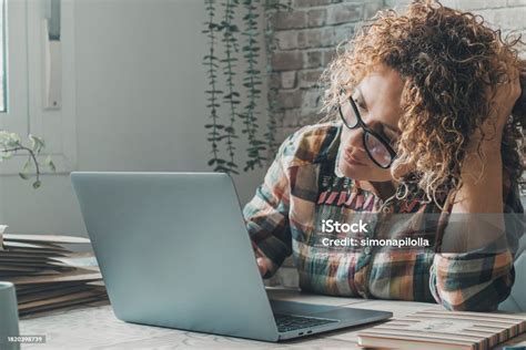 현대의 한 프리랜서 기업가 여성은 소규모 비즈니스 사무실 직장에서 집에서 노트북으로 작업하면서 머리를 만지고 의심과 호기심으로 디스플레이 컴퓨터를 봅니다 온라인 여성