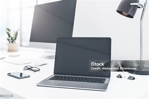 배경에 검은 램프 스마트 폰 및 컴퓨터 모니터가있는 라이트 테이블의 로고 또는 텍스트에 대한 반사 및 복사 공간이있는 빈 검은 색 현대 노트북 화면 3d 렌더링 모형 0명에