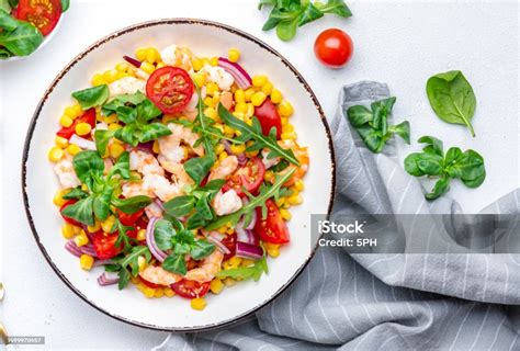 하얀 테이블 배경에 새우 옥수수 아보카도 붉은 방울 토마토 양고기 양상추 양파를 곁들인 신선한 맛있는 샐러드 평면도 어린양 잎