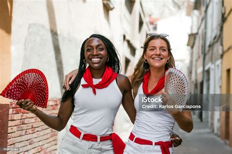 두 명의 젊은 백인과 아프리카 계 미국인 소녀가 손 팬과 함께 스페인에있는 마을의 전통적인 축제를 즐깁니다 다양성 관용 및