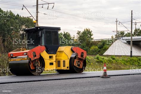 무거운 진동 롤러 압축기아스팔트 도로 롤러는 도로 건설 현장의 도로에 새로운 뜨거운 아스팔트를 누릅니다 아스팔트 포장 작업에서 무거운 진동 롤러 복구 도로에 대한 스톡 사진