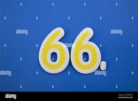 The Number 66 In Yellow Photographed From Above Placed On A Blue