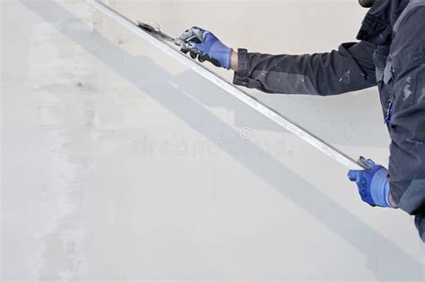 The Hand Holds A Metal Rule For Leveling The Plaster On The Walls Applying Gypsum Plaster In A