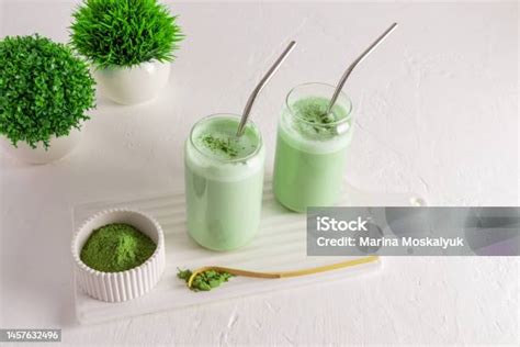녹색 말차 가루 한 그릇과 함께 화이트 보드에 녹차 말차 라떼와 맥주 캔 형태의 두 개의 현대 안경 천연 유기농 음료 0명에