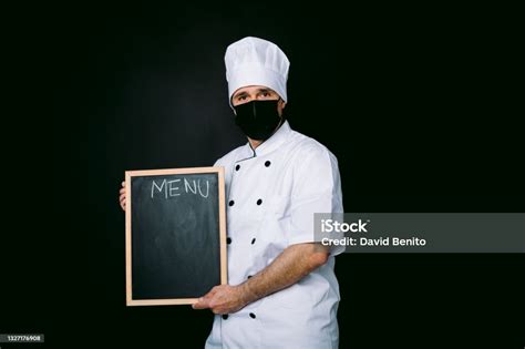 요리 재킷과 모자를 쓰고 검은 색 마스크를 쓰고 메뉴가 있는 칠판을 검은 색 배경에 들고 있는 셰프 요리사 40 44세에 대한