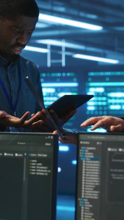 Vertical Engineers Working In High Tech Server Farm Using Laptop And