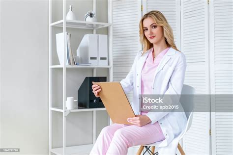 젊은 행복한 여자 의사는 검사 전에 환자의 기억 상실을 검사하고 개인 클리닉의 의자에 앉아 그녀의 손에 클립 보드를 들고 있습니다 20 24세에 대한 스톡 사진 및 기타