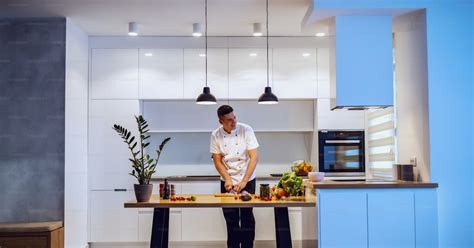 하얀 유니폼을 입고 웃고 있는 백인 요리사의 전체 길이 양파를 자르고 식사를 준비합니다 주방 카운터에는 야채와 향신료가 있습니다 사진 Unsplash의 세르비아 이미지