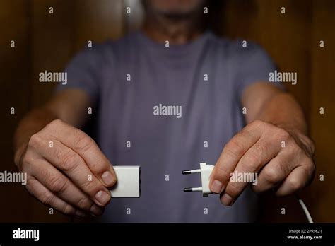 A Man While Disconnecting An Electrical Socket From The Plug Stock