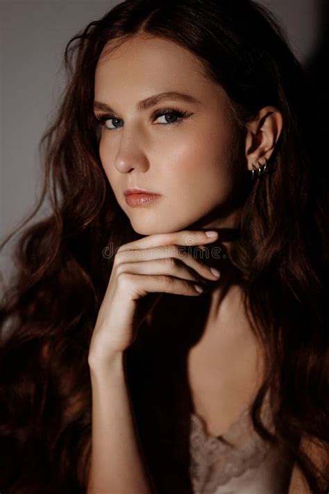 A Woman With Long Brown Hair And Blue Eyes Is Posing For A Photo Stock