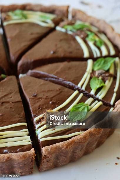 슬라이스 민트 초콜릿 타르트 바삭바삭하고 플루트 코코아 페이스트리 크러스트 화이트 초콜릿파이프 민트 잎 잔가지로 장식된 부스러기와 초콜릿 조각 대리석 효과 배경 전경에