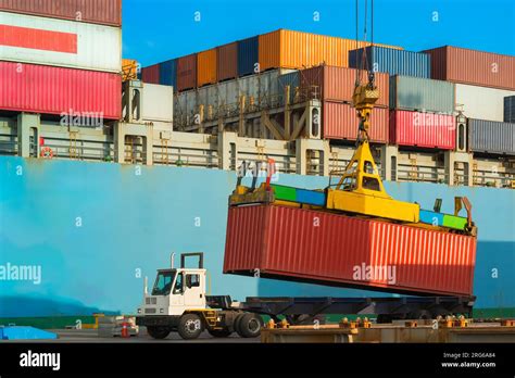 A Container Being Unloaded From A Cargo Ship And Being Loaded Onto A Truck At A Port In Chile