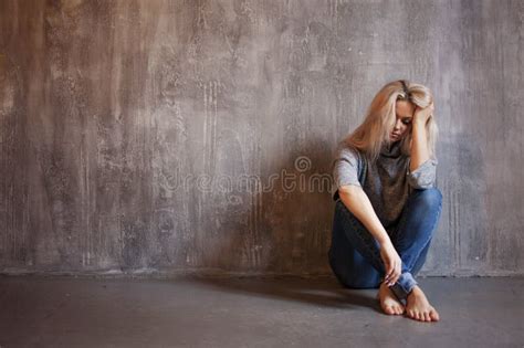 Унылая женщина сидит на поле Депрессия и хроническая усталость Молодая красивая блондинка в