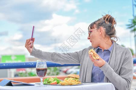 女人吃汉堡包和做自拍快餐概高清图片下载 正版图片506285295 摄图网