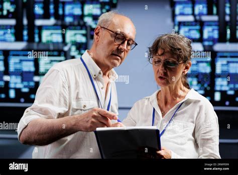 Elderly Computer Scientists Monitoring Data Center Racks Optimizing Them For Data Processing