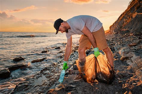 오염으로부터 해변을 청소하십시오 플라스틱 병을 집어 드는 자원 봉사자 배경 바다와 일몰 공간을 복사합니다 환경 보전의 개념 사람들에 대한 스톡 사진 및 기타 이미지 Istock