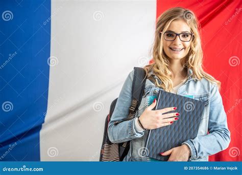 Молодой ученик с расчалками держит учебник перед флаг Франции Стоковое Фото изображение