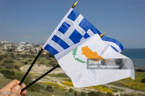 Banderas Chipriotas Y Griegas En La Mano Frente Al Mar El Cielo Y El