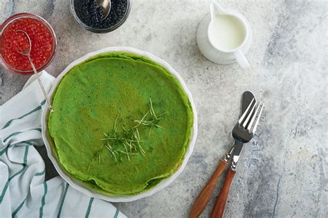 녹색 팬케이크 회색 콘크리트 배경에 빨간색과 검은색 캐비어와 요구르트 소스를 곁들인 둥근 얇은 녹색 시금치 크레이프 팬케이크 건강한 채식 아침 식사 전국 팬케이크의 날 또는