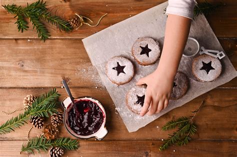 나무 테이블에 별 모양의 크리스마스 쿠키 잼과 분말 가문비 나무 가지로 만든 장식 비키트 프레임에 어린이의 손 위에서 볼 수 있습니다 복사 공간 개념에 대한 스톡 사진 및