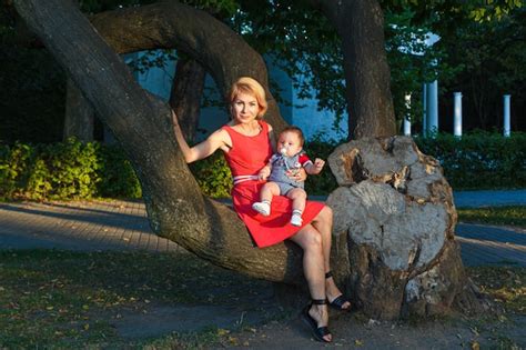 Hermosa Madre Con Un Hijo Sentado En Un árbol En El Parque En Verano Foto Premium