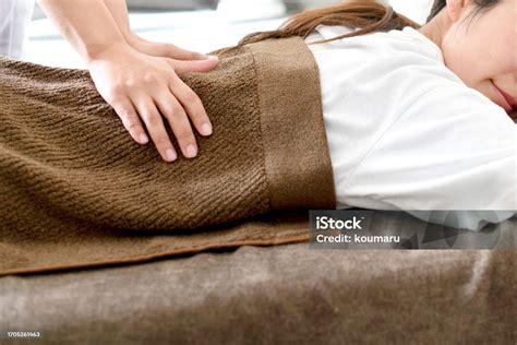 A Young Asian Woman Lying Face Down Receiving Massage Treatment In Bed