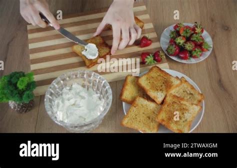 Womens Hands Putting Cheese Spread On A Toasted White Bread