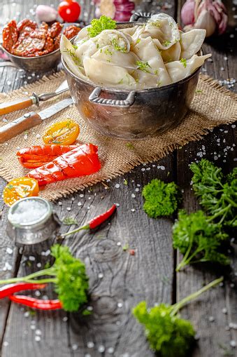 빈티지 소박한 그릇 접시 포크 나이프 숟가락 소금 향신료 신선한 허브 스탠드 와 거짓말 다른 각도 나무 절단 부엌 테이블에 어두운 빛에 빨간색과 흰색 생선 고기로 만든 만두