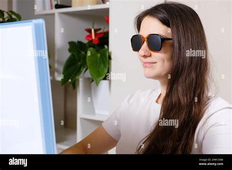 A Woman Looks At A Computer Screen Through Perforated Glasses With Holes To Improve Vision In