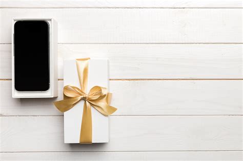 골드 리본과 스마트폰이 있는 기프트 박스를 컬러 배경 상단 보기로 오픈했습니다 빈 오픈 박스 포장 모형 디자인템플릿 브랜딩 모형