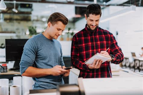 테이블에 서서 프로젝트를 진행하는 긍정적인 젊은 남성 스타트업 사진 Unsplash의 산업 이미지