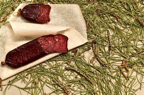 알 사슴 고기로 만든 말린 소시지 양피지 큰 조각에 조각으로 잘라 소나무 바늘로 만든 바닥 가공육에 대한 스톡 사진 및 기타