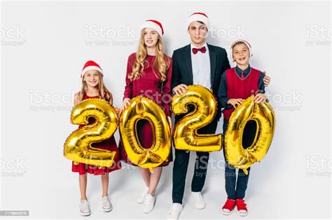 흰색 배경에 숫자 2020 모양의 풍선을 들고 산타 모자를 쓰고있는 아이들과 함께 하는 젊은 행복한 가족 12월에 대한 스톡