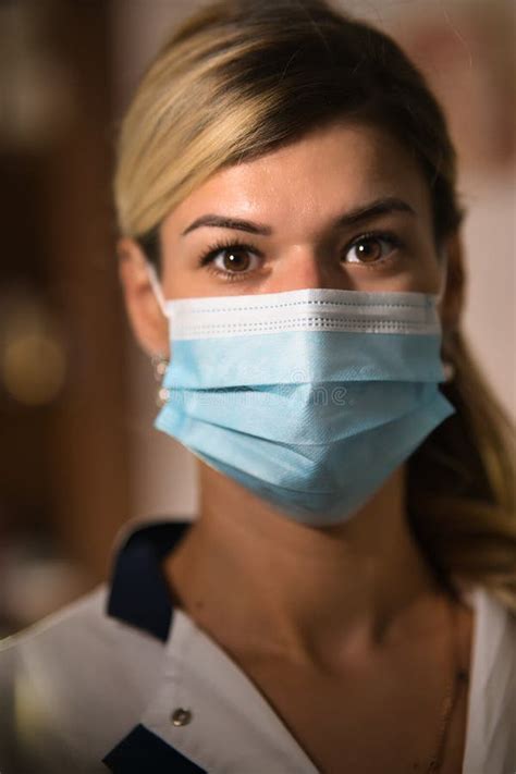 Vertical Portrait Of A Young Nurse In A Mask Looking Straight Into The
