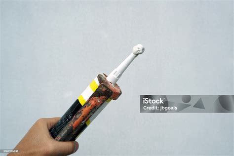 실리콘 실란트가 있는 코킹 건을 들고 있는 손을 닫고 뒷면에는 흰색 시멘트 벽이 있습니다 0명에 대한 스톡 사진 및 기타 이미지 0명 개선 거친 Istock