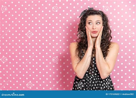 Kinky Young Pinup Girl With Thoughtful Face Expression Keeping Her Hands On Cheeks Looking To