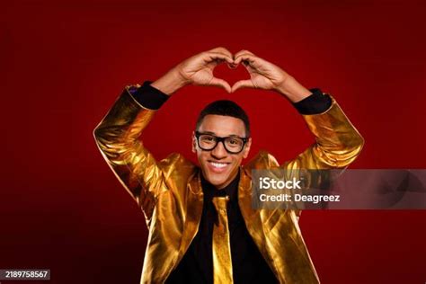 반짝이는 황금색 양복을 입은 젊은 남자가 생생한 붉은 배경을 배경으로 손으로 하트 모양을 만들고 있습니다 30 34세에 대한 스톡 사진 및 기타 이미지 Istock