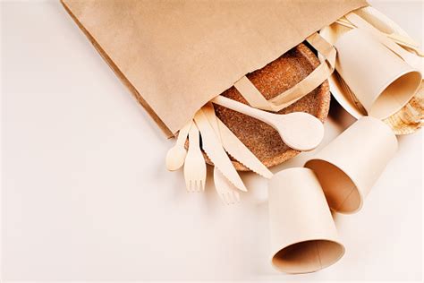 에코 공예 종이 식기 컵 패스트 푸드 용기 재활용 환경 친화적 인 개념 일회용 에코 칼 붙이 접시 숟가락 나이프 가벼운 배경에 포크 음식 배달을위한 종이 봉지를 제작하십시오