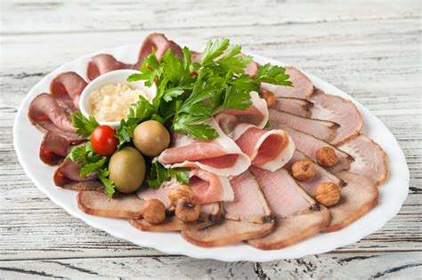 육류와 소시지와 견과류 접시에 슬라이스 마늘 소스 훈제 고기 구운 햄 쵸 릿 죠 베이컨 올리브 체리 토마토 흰색 질감된 나무 테이블의 배경에 대 한 접시에 고기에 대한 스톡