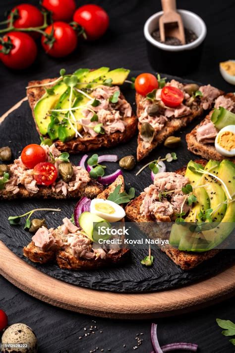 참치로 토스트를 설정합니다 통조림 참치 메추라기 달걀 체리 토마토 아보카도 마이크로 그린 및 케이퍼와 이탈리아 브루 쉐타 샌드위치 맛있는 아침 식사 또는 스낵 위쪽 보기 0