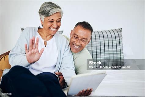 디지털 태블릿 영상 통화 노부부가 집 소파에서 손을 흔들며 유대감을 형성하고 있다 행복하고 미소를 짓고 은퇴한 노인 남성과 여성은 집에서 모바일로 가상 대화를 나눕니다 2