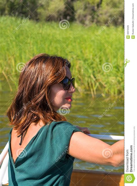 Красивая молодая женщина в зеленой блузке солнечных очках сидя на палубе шлюпки Стоковое Фото