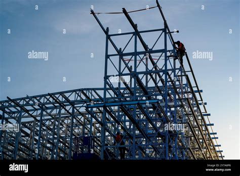 Workers Working At Height On Clad Rack Structure Installing Steel