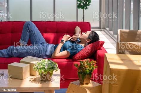 젊은 아시아 여성 바닥에 골판지 상자와 새로운 집에 골판지 상자를 포장 한 후 빨간 편안한 소파에 휴식 빨강에 대한 스톡 사진 및 기타 이미지 Istock