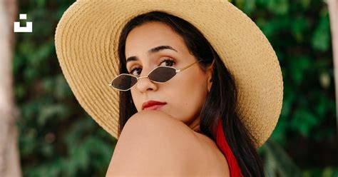 갈색 태양 모자를 쓰고 빨간색과 흰색 꽃 튜브 드레스를 입은 여자 사진 Unsplash의 무료 유행 이미지