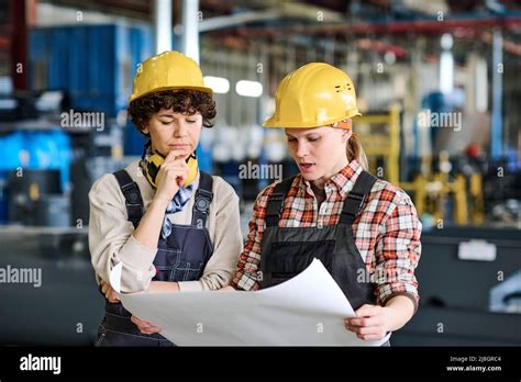 Pensive Female Engineer Looking At Sketch On Blueprint Held By