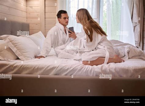 Lady Showing Phone Screen To Man While Sitting On Bed Stock Photo Alamy