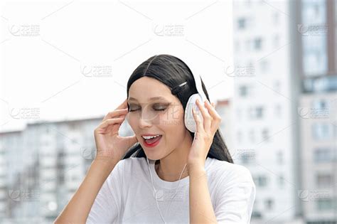 十几岁的女孩在户外戴着耳机欣赏音乐